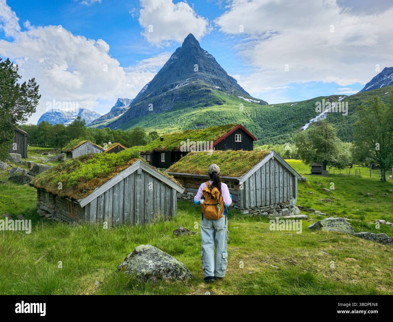 A traveler explores the lush green landscape of Innerdalen Norway ...