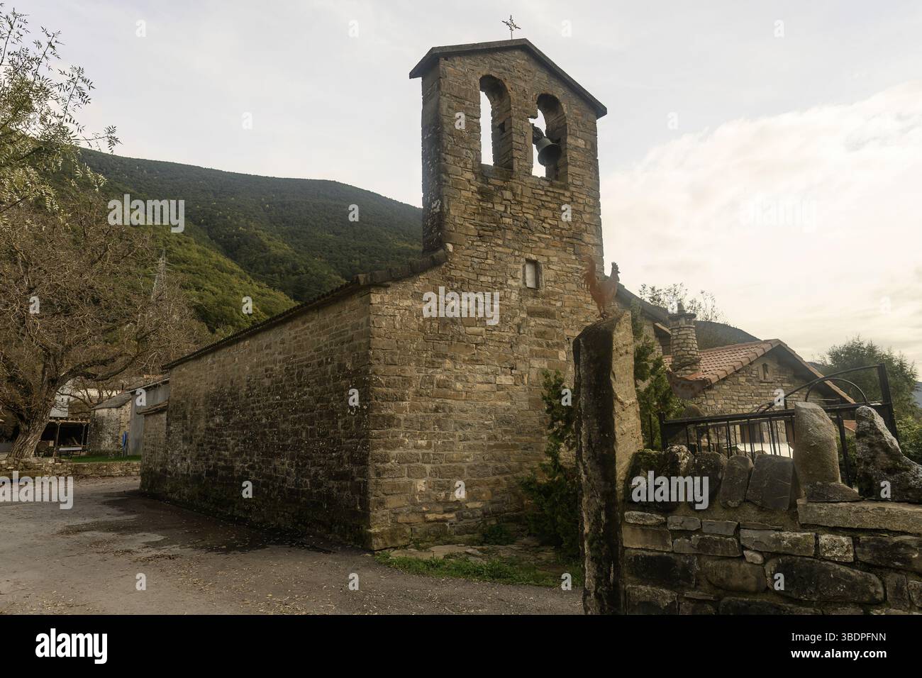 Small stone church with a bell tower and adjacent cemetery, set in a ...