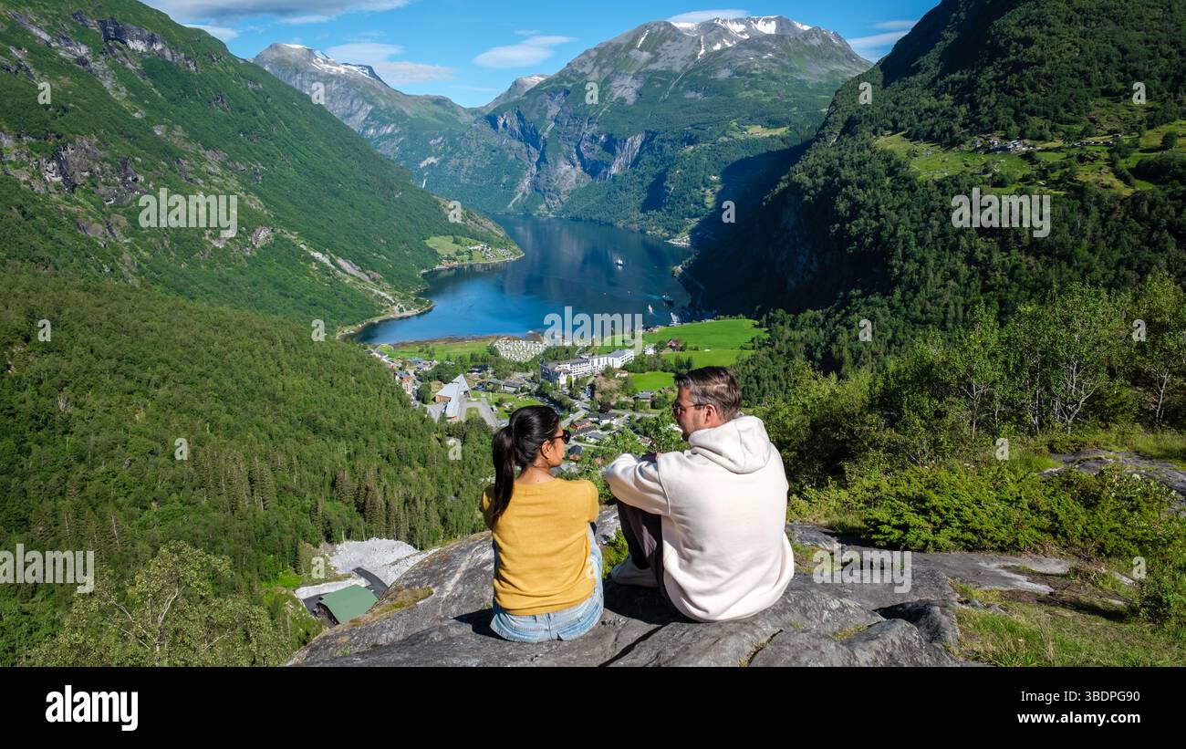 A couple relaxes on a rocky outcrop overlooking the breathtaking ...