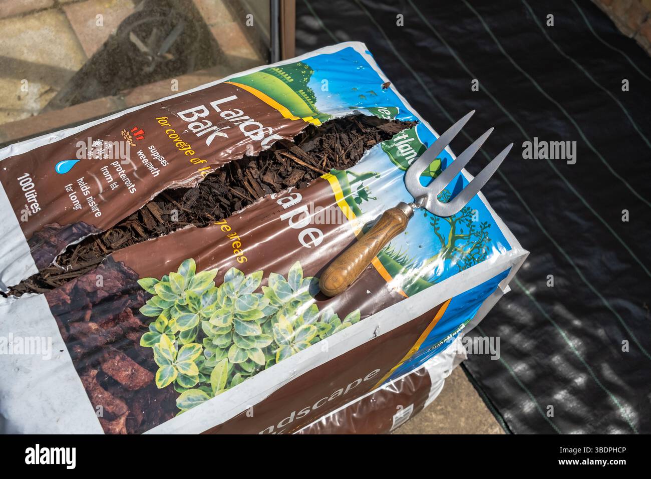 Garden fork on a bag of wood bark Stock Photo - Alamy