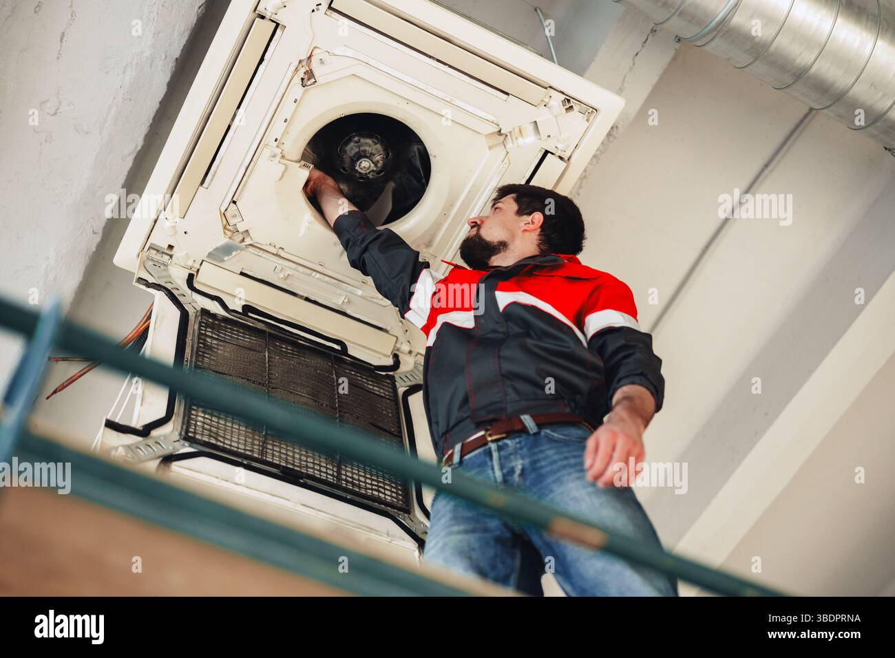 Technician performs maintenance on air conditioning unit in commercial ...