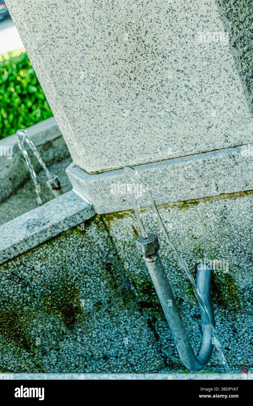 Water cascades from a stone fountain into a shallow basin. The fountain ...
