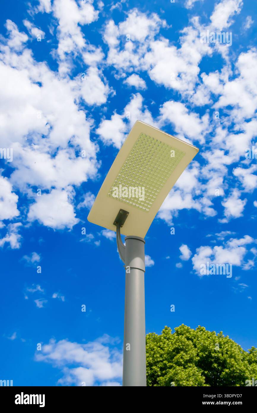 A modern street lamp stands tall in a vibrant park, its bright light ...