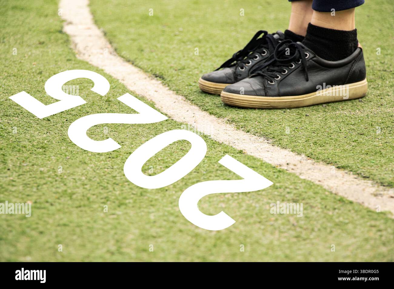 Feet in sneakers on a football field near the line with the inscription ...