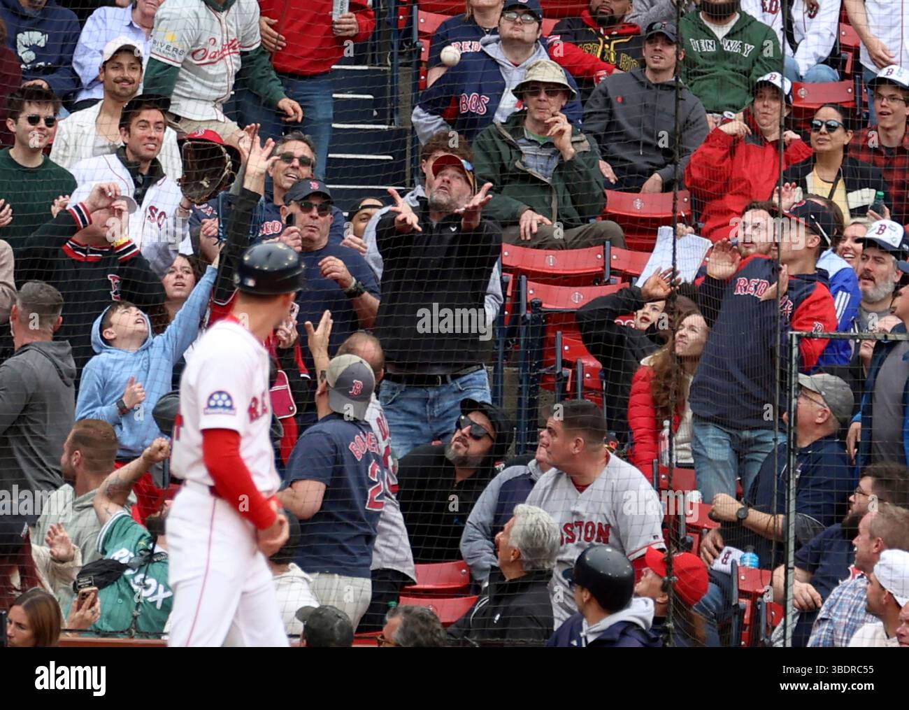 A fan grabs a foul ball during the ninth inning of a baseball game ...