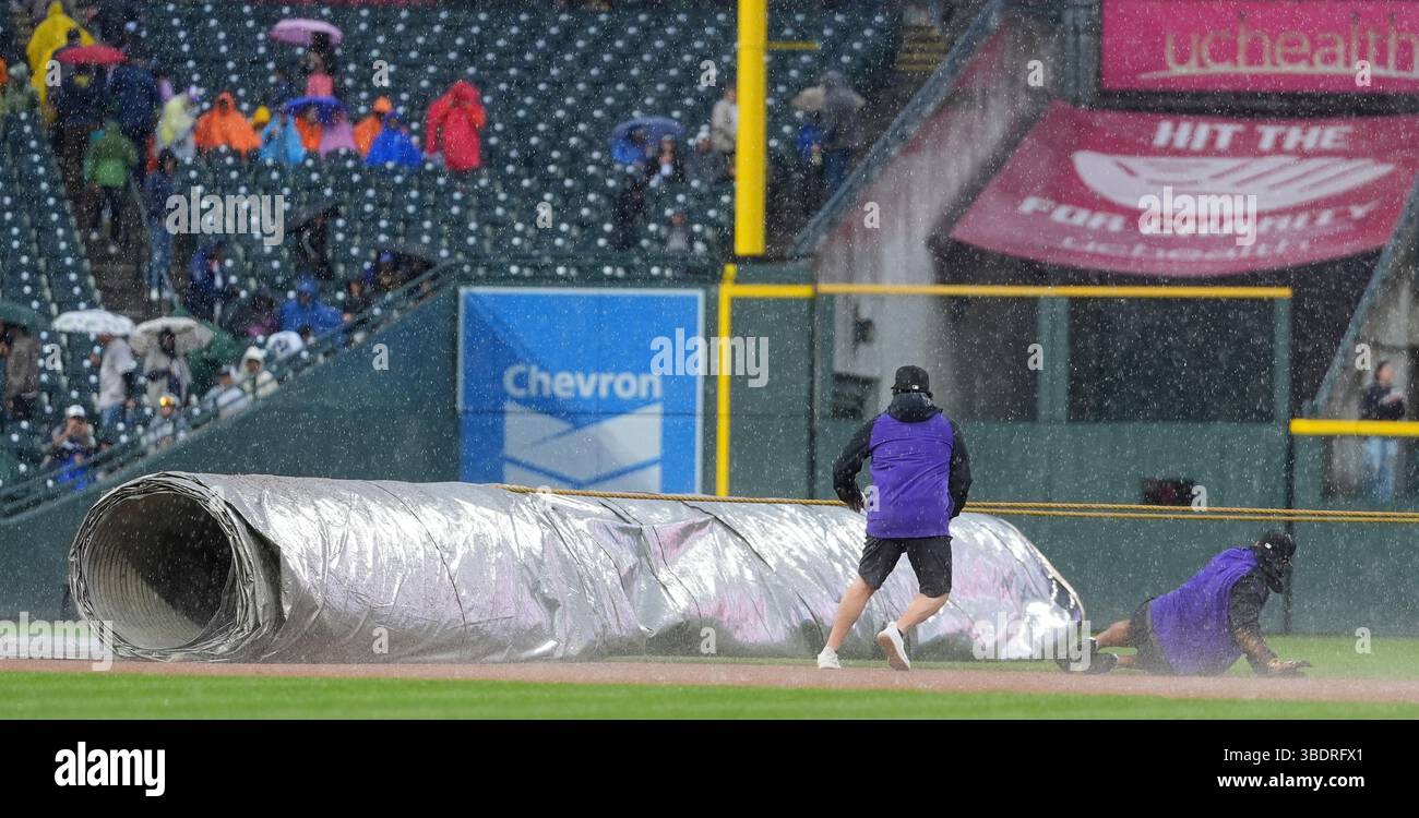 Grounds crew members struggle to pull the tarpaulin during a rain delay ...