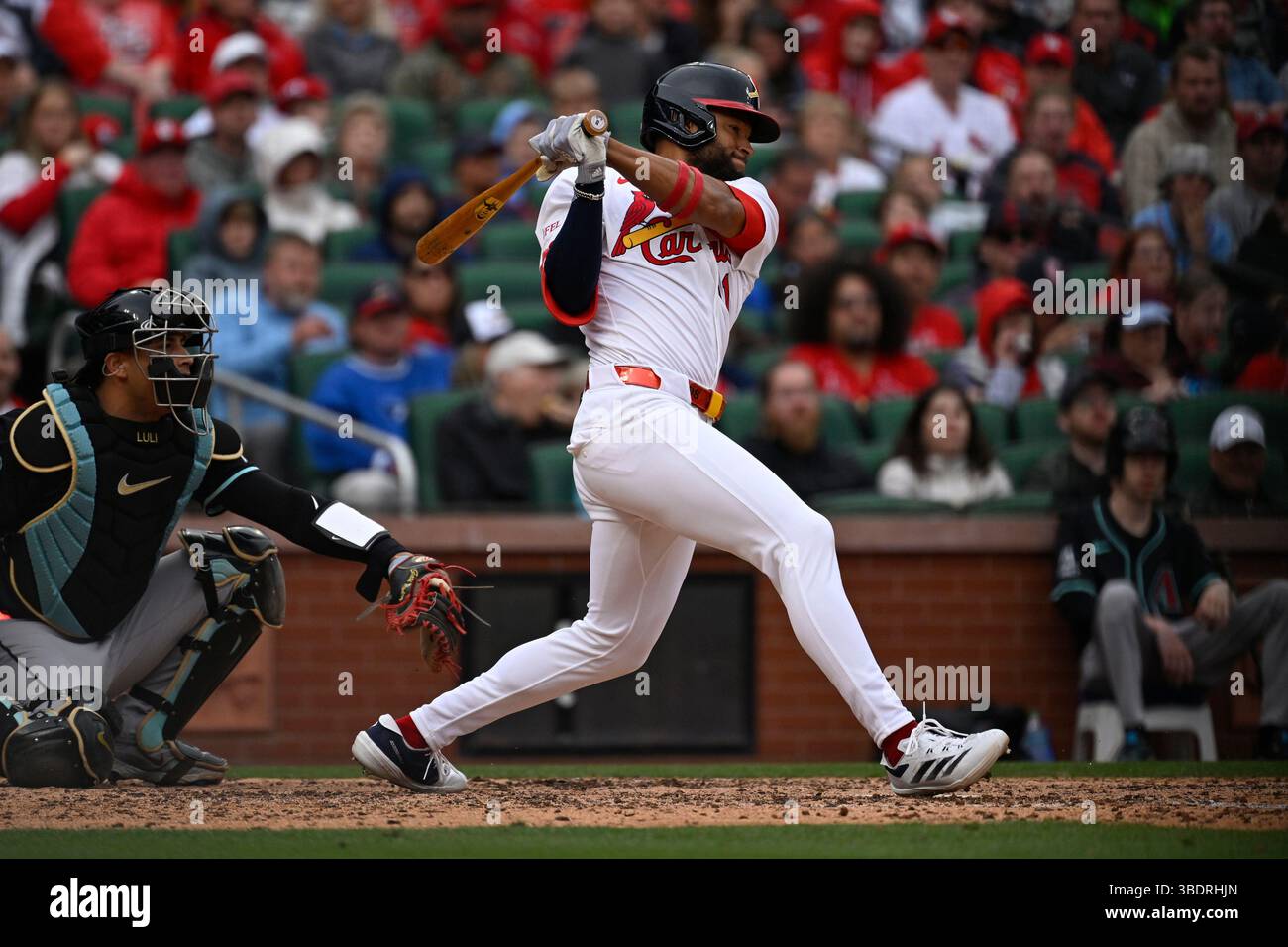 St. Louis Cardinals' Victor Scott II, right, hits an RBI single next to ...