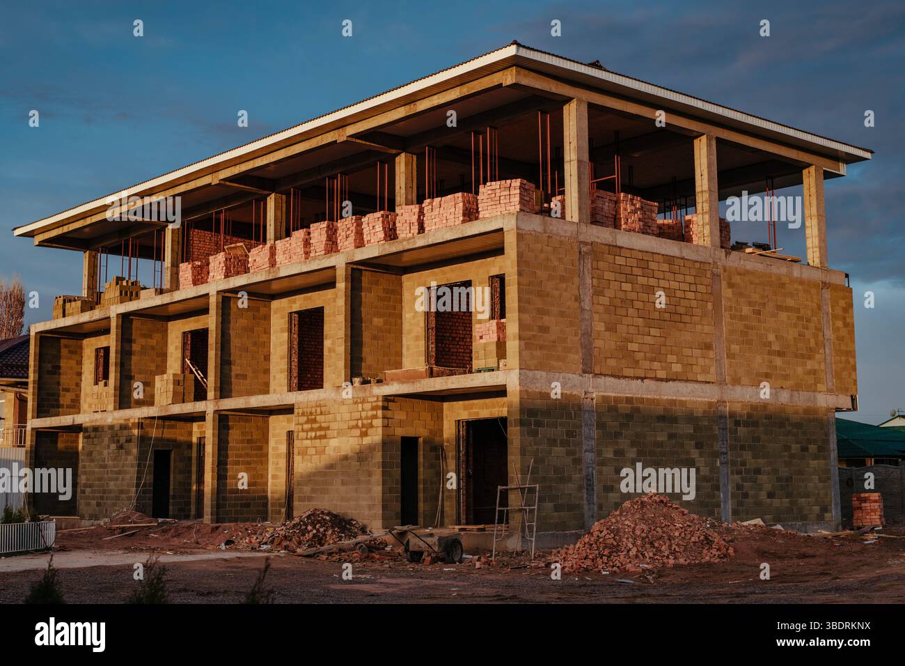 Construction of three-storey building at sunrise light Stock Photo - Alamy