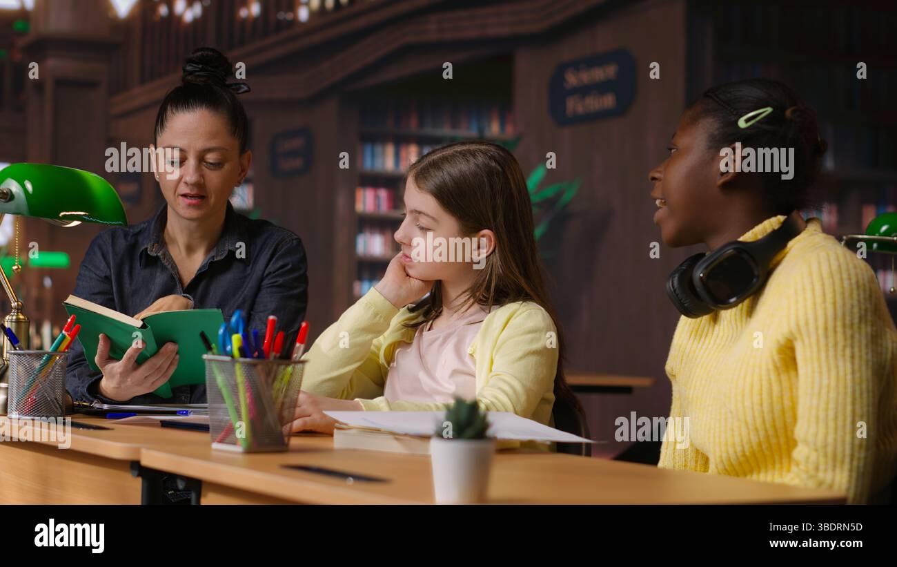 Female tutor mentoring schoolgirls in a school library setting ...