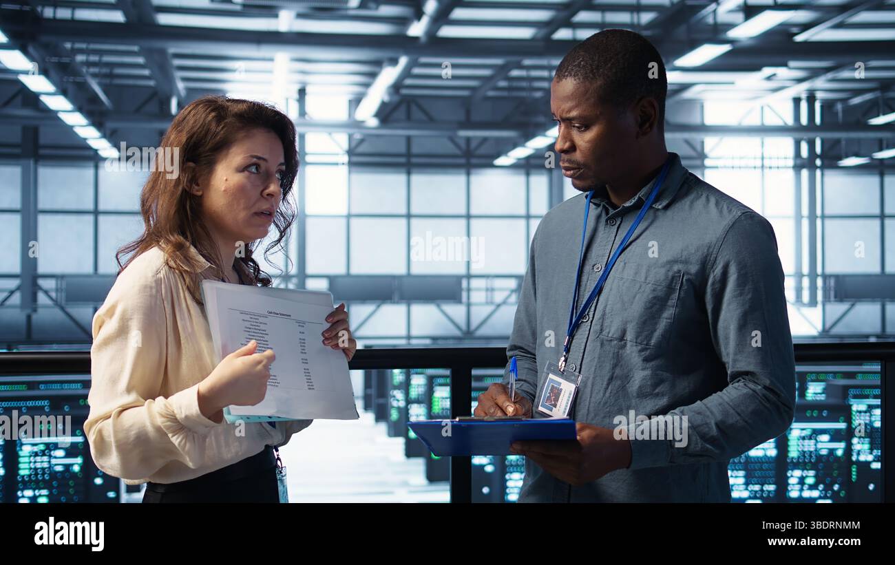 Data center team reviewing paperwork files in high tech server room ...