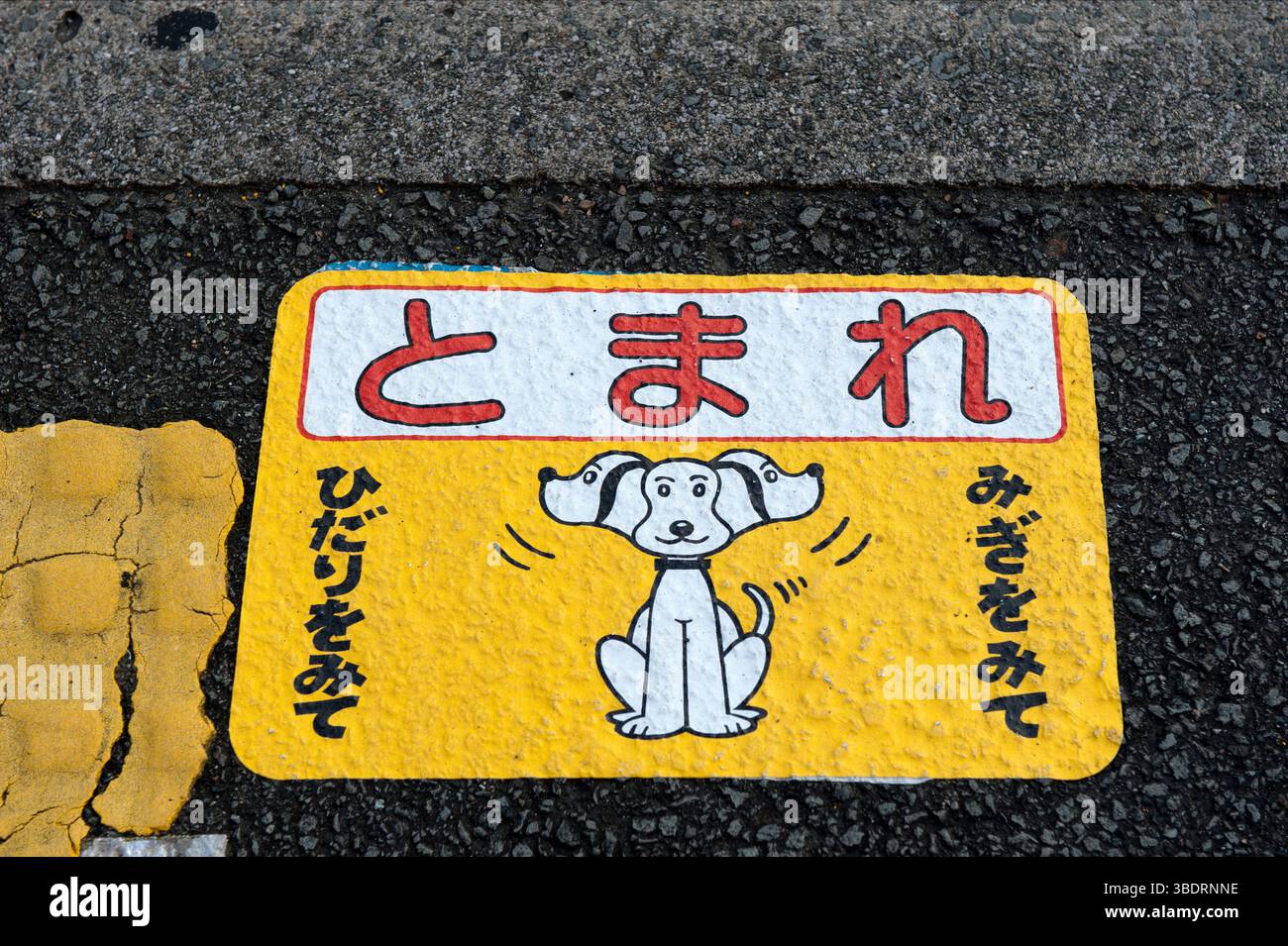 A Japanese sidewalk caution sign for children reading "tomare" (stop ...