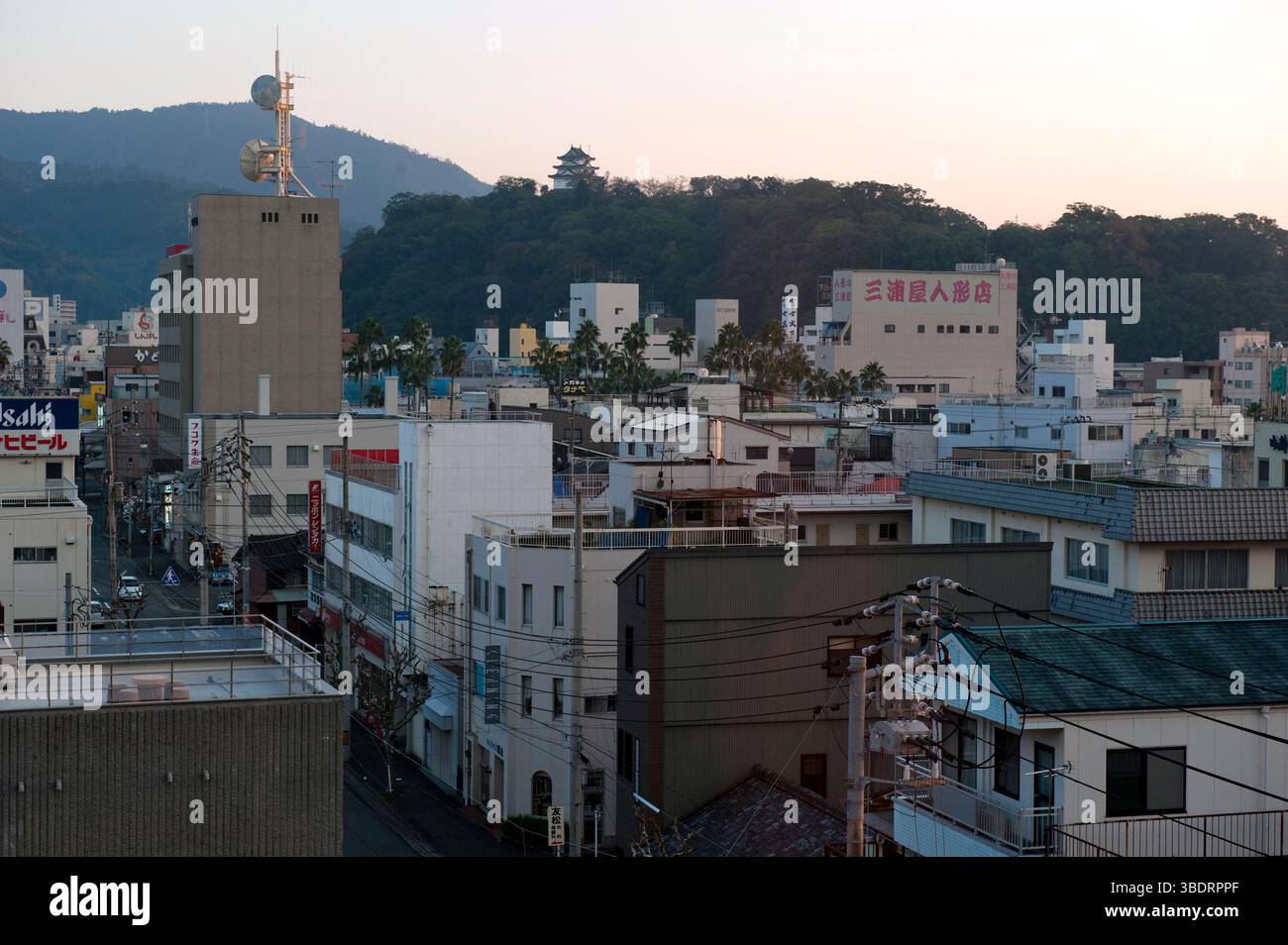 Uwajima Castle looks over concrete buildings comprising the downtown ...