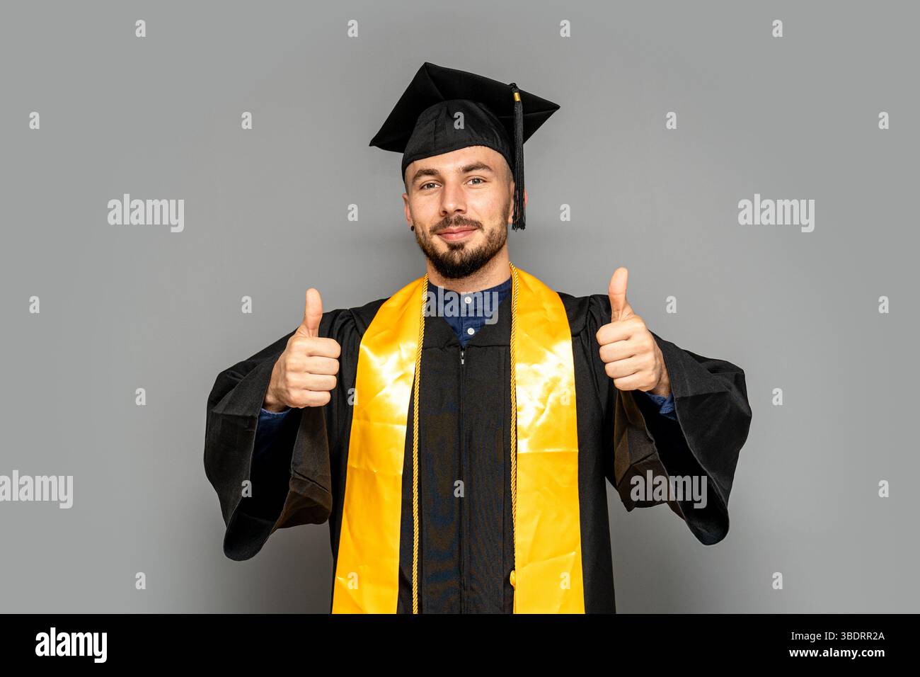 Happy graduate gesturing thumbs up celebrating graduation Stock Photo ...