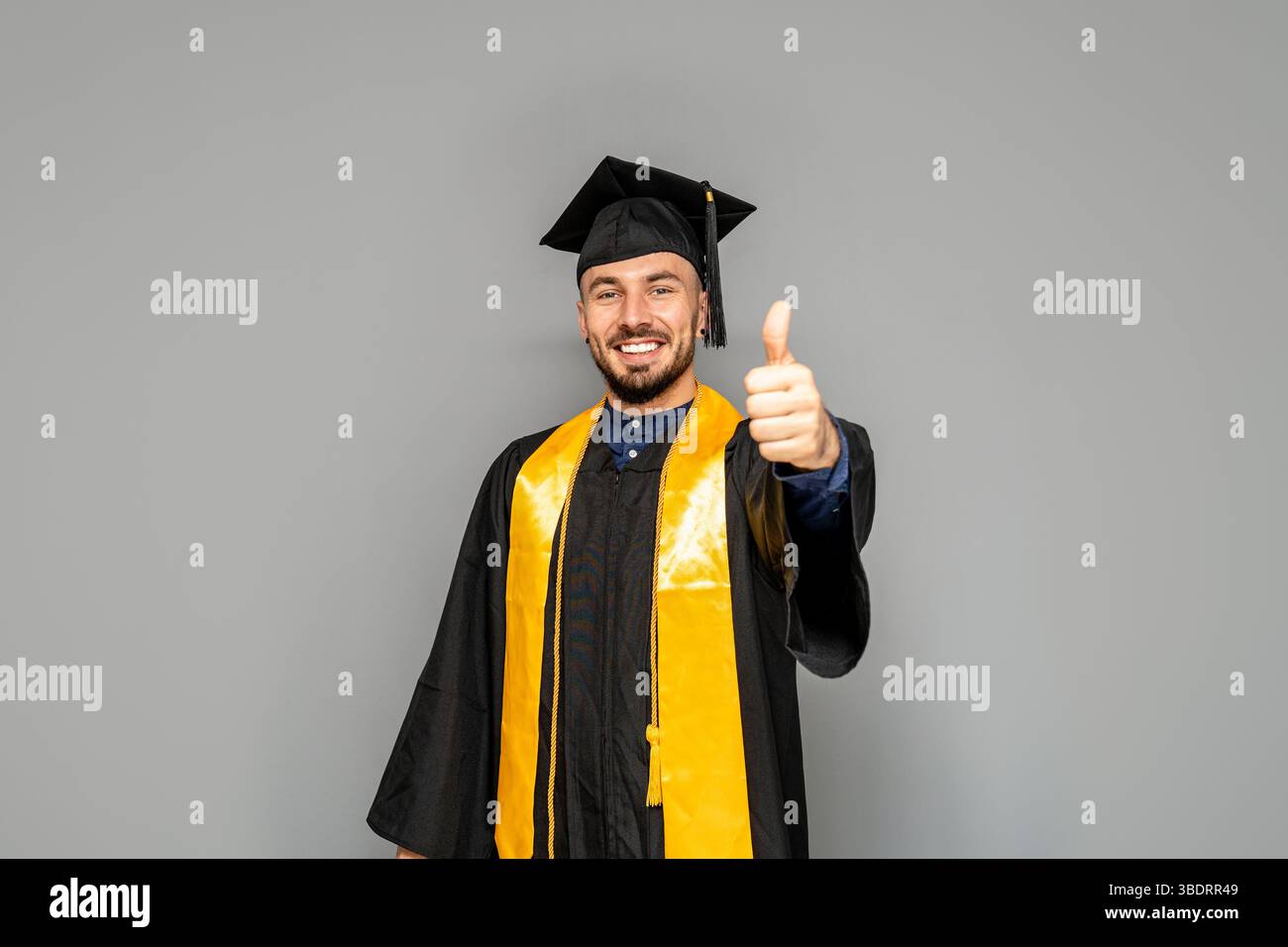 Happy graduate gesturing thumbs up celebrating graduation Stock Photo ...