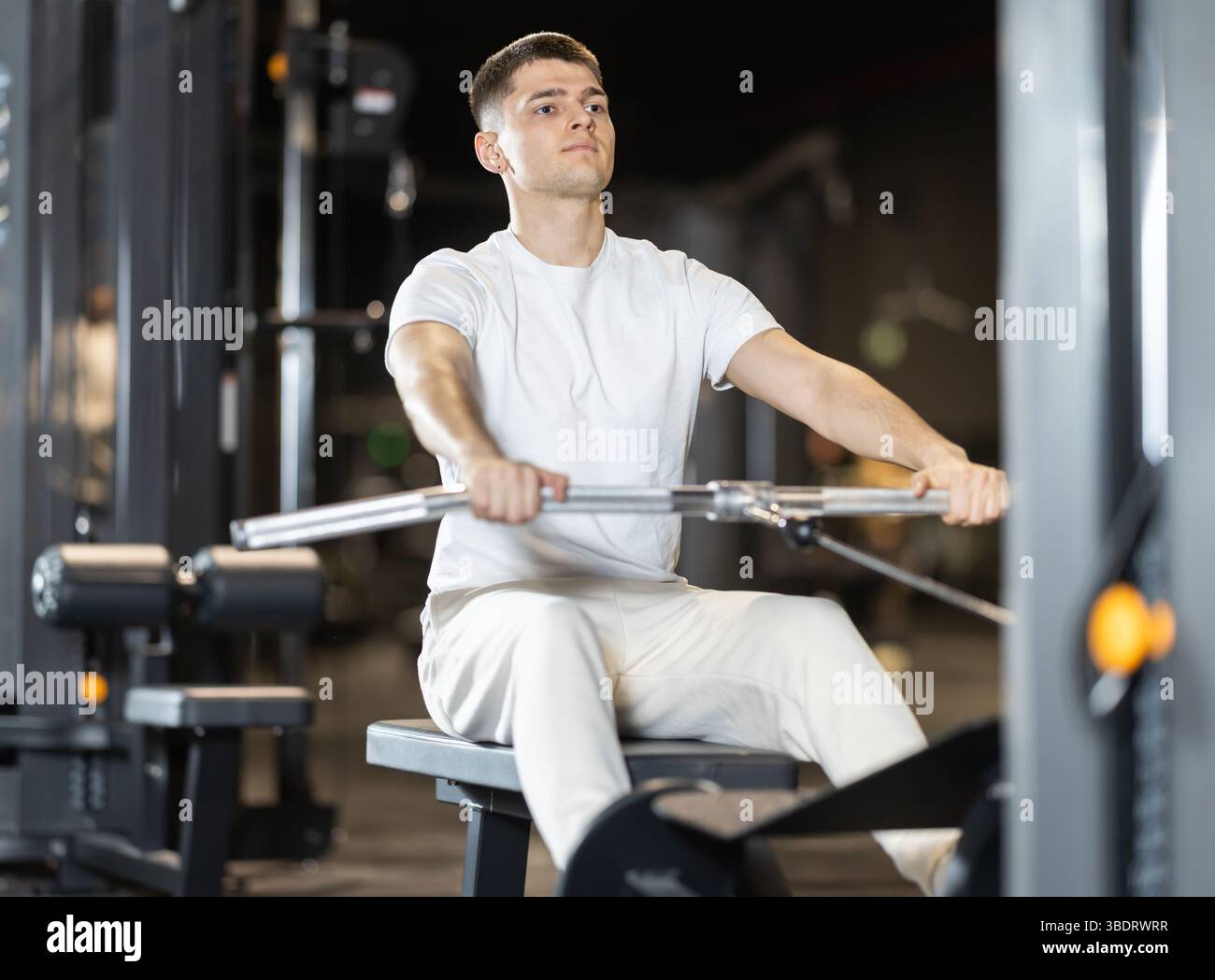 Guy working out back muscles on seated cable row machine in gym Stock ...