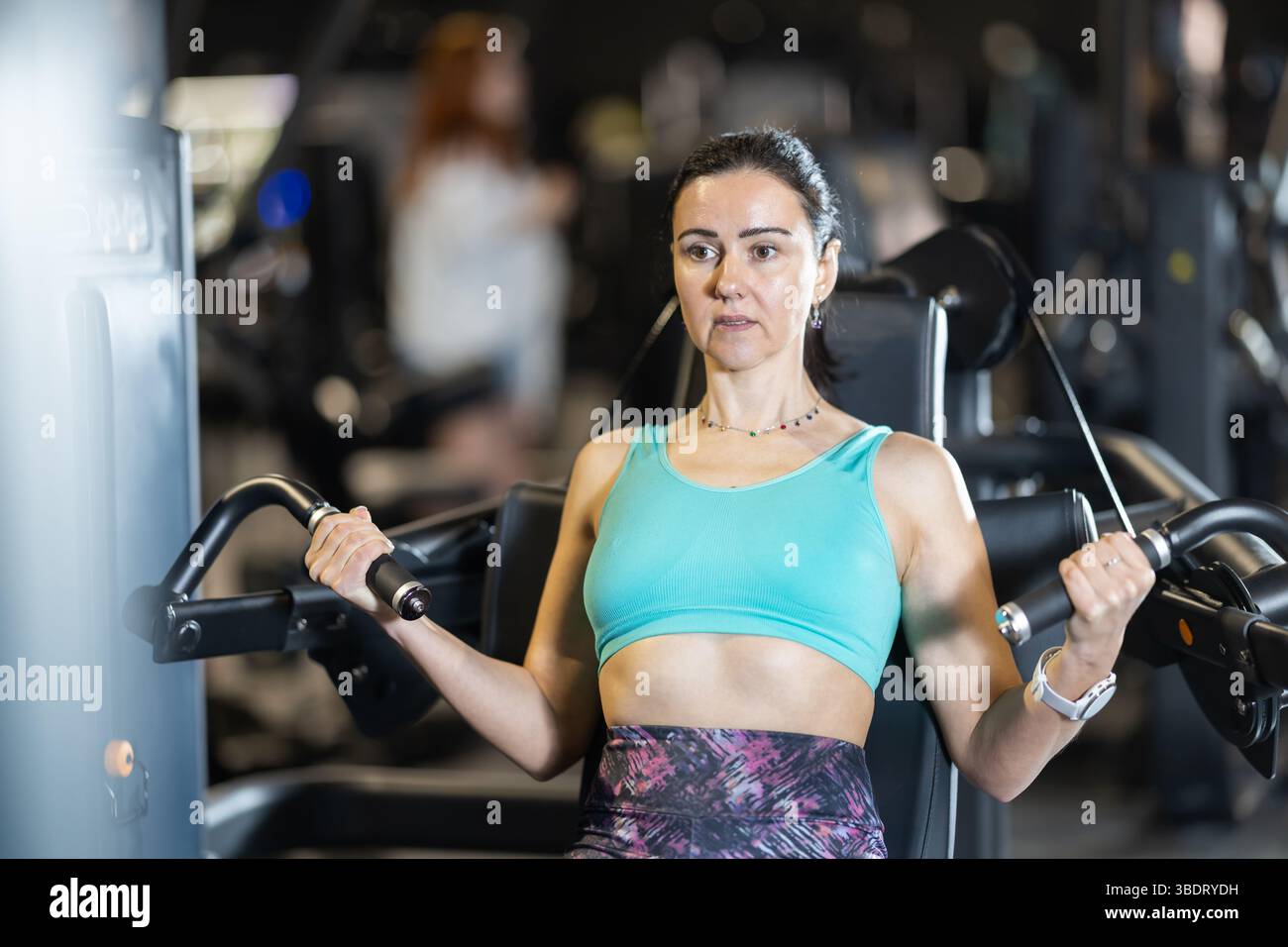 In gym, woman uses chest press machine to strengthen arm muscles Stock ...