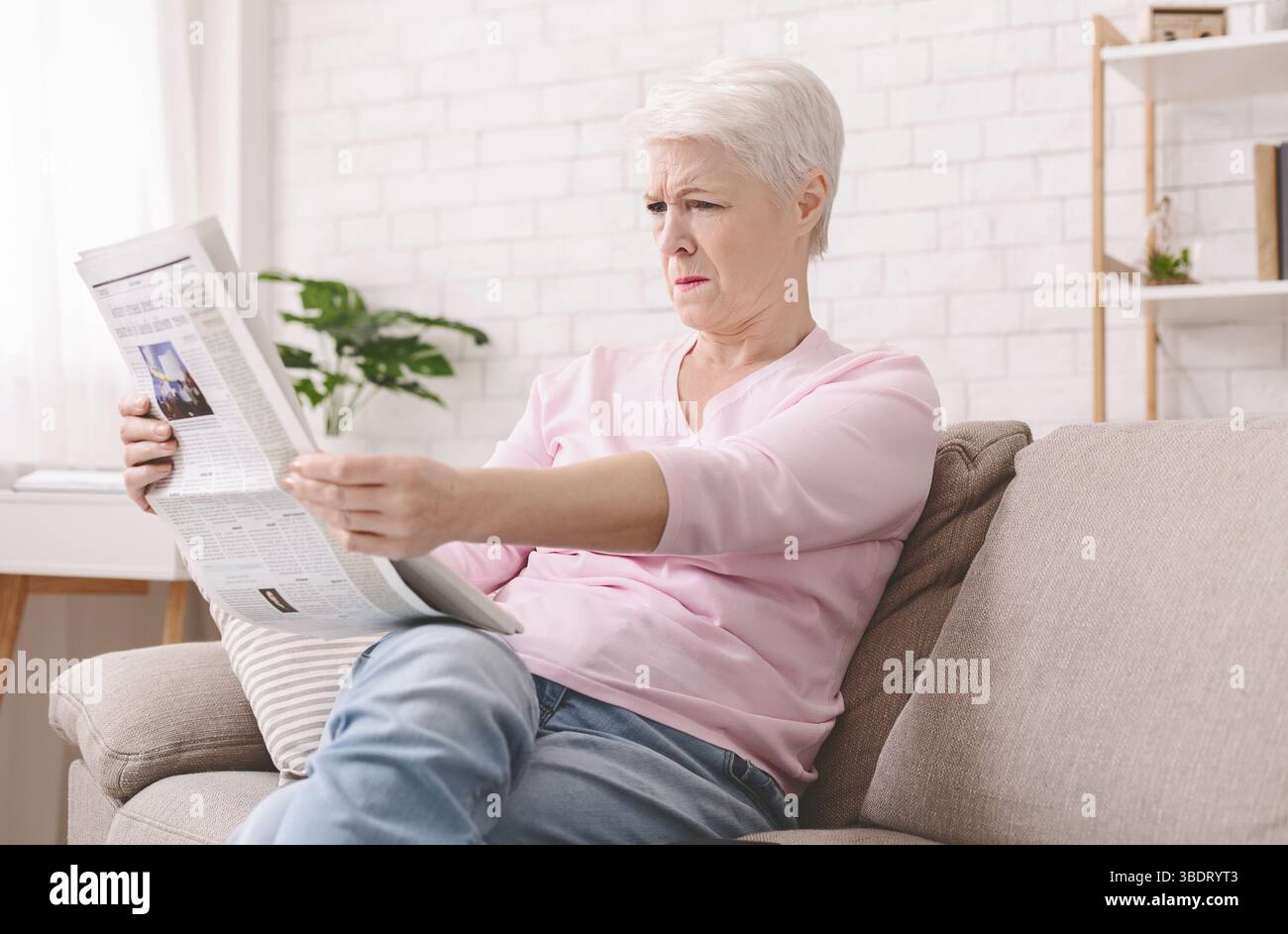 Senior lady squinting and holding newspaper far from eyes Stock Photo ...
