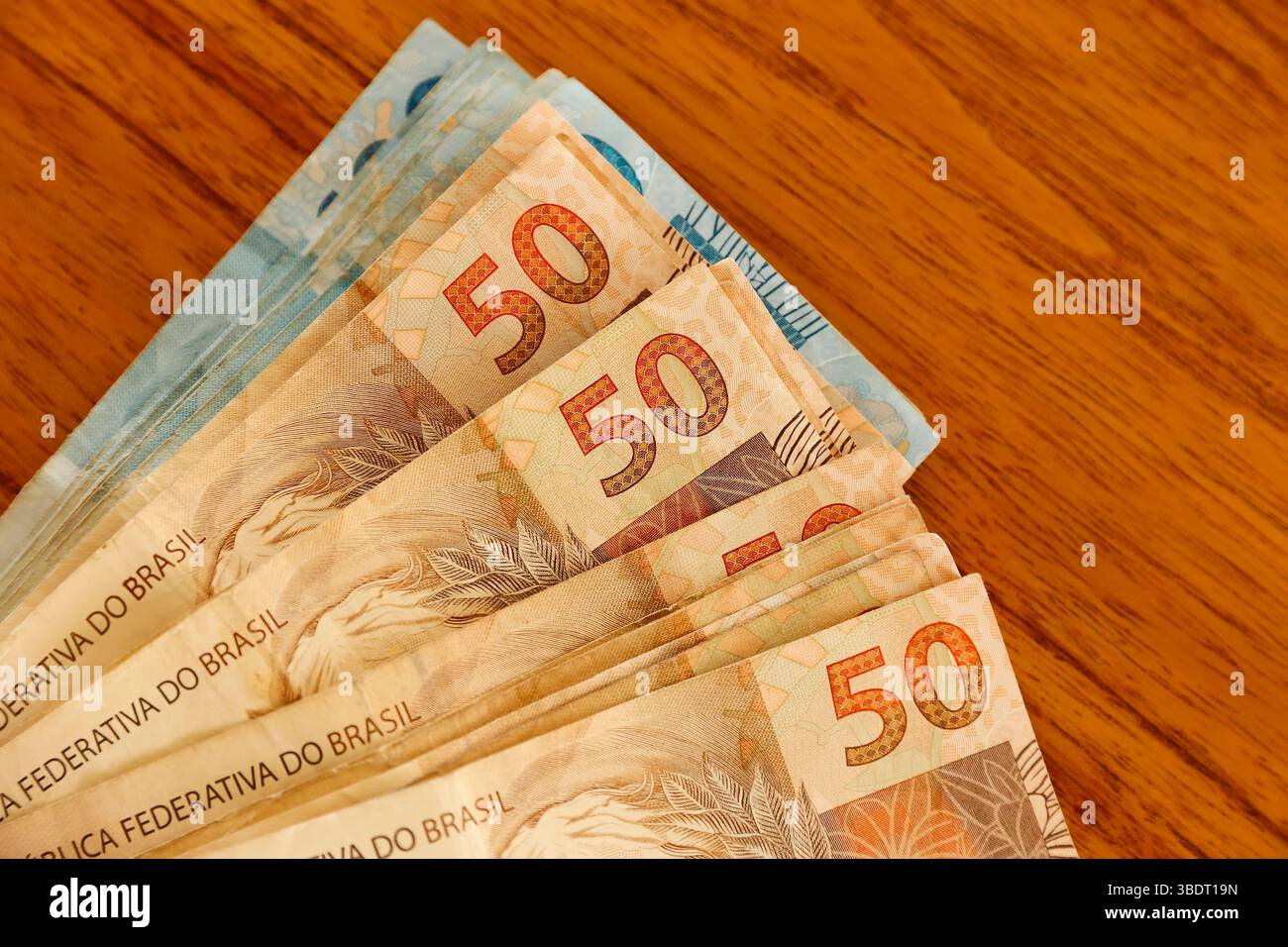 Fifty real bills in foreground on wooden table, with one hundred real ...