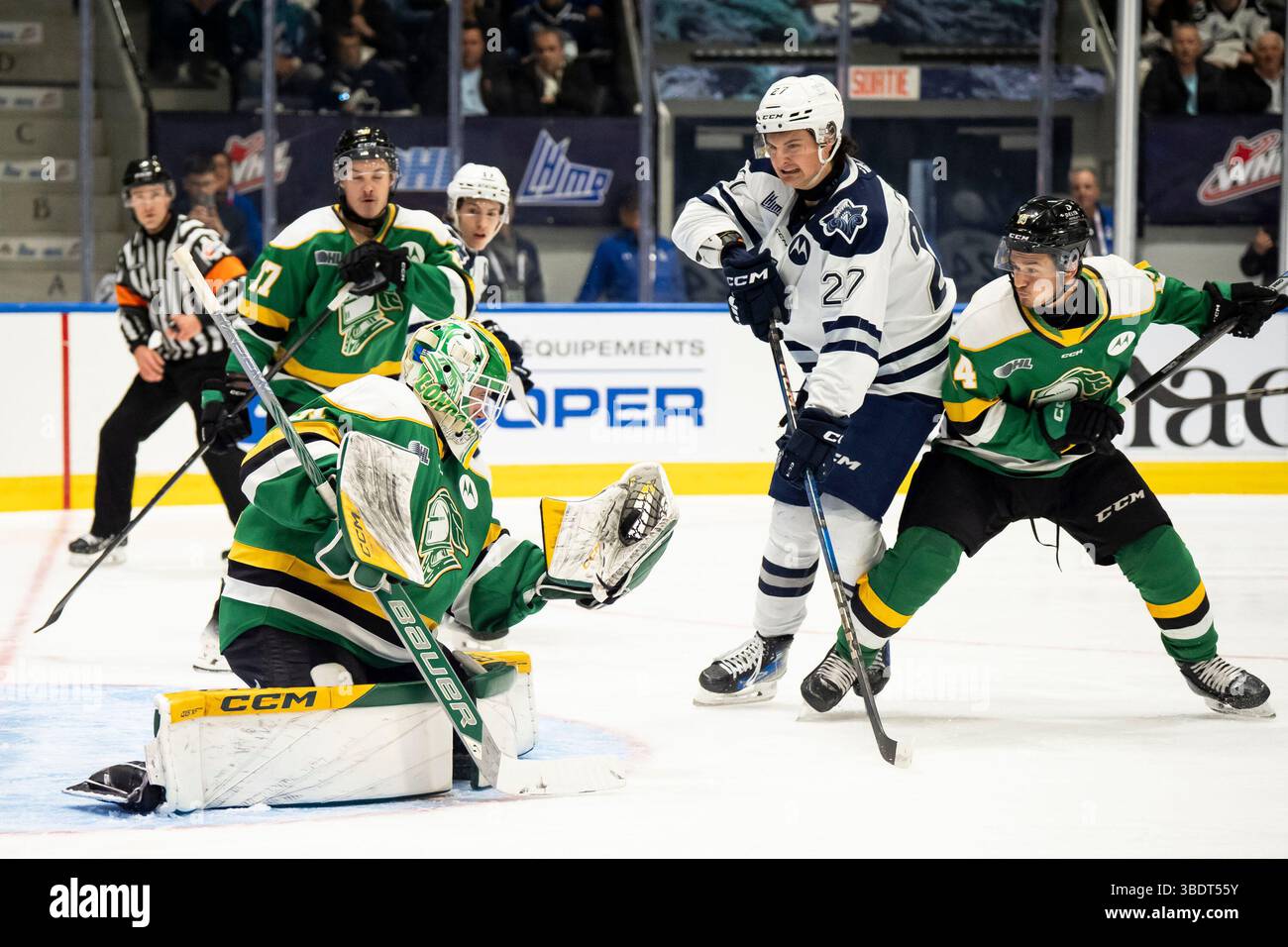 London Knights goaltender Austin Elliott, front left, makes a save ...