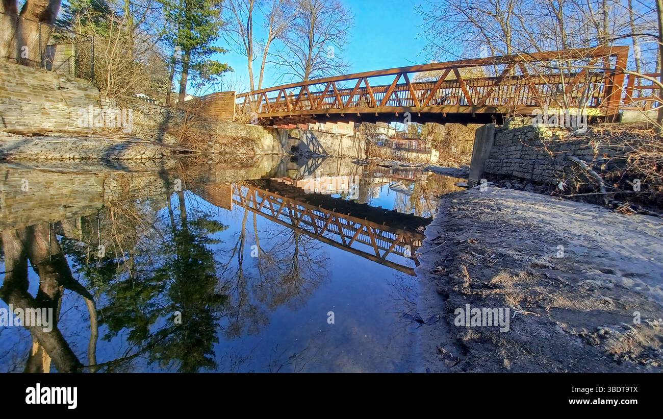The Culham Trail Bridge spans a calm waterway, reflecting the structure ...