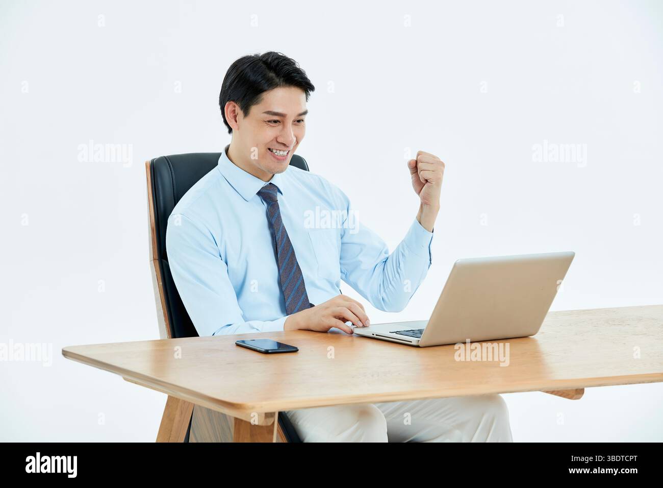 a young suited man excitedly raising both hands at his desk Stock Photo ...
