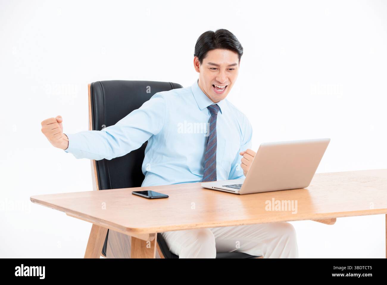 a young suited man excitedly raising both hands at his desk Stock Photo ...