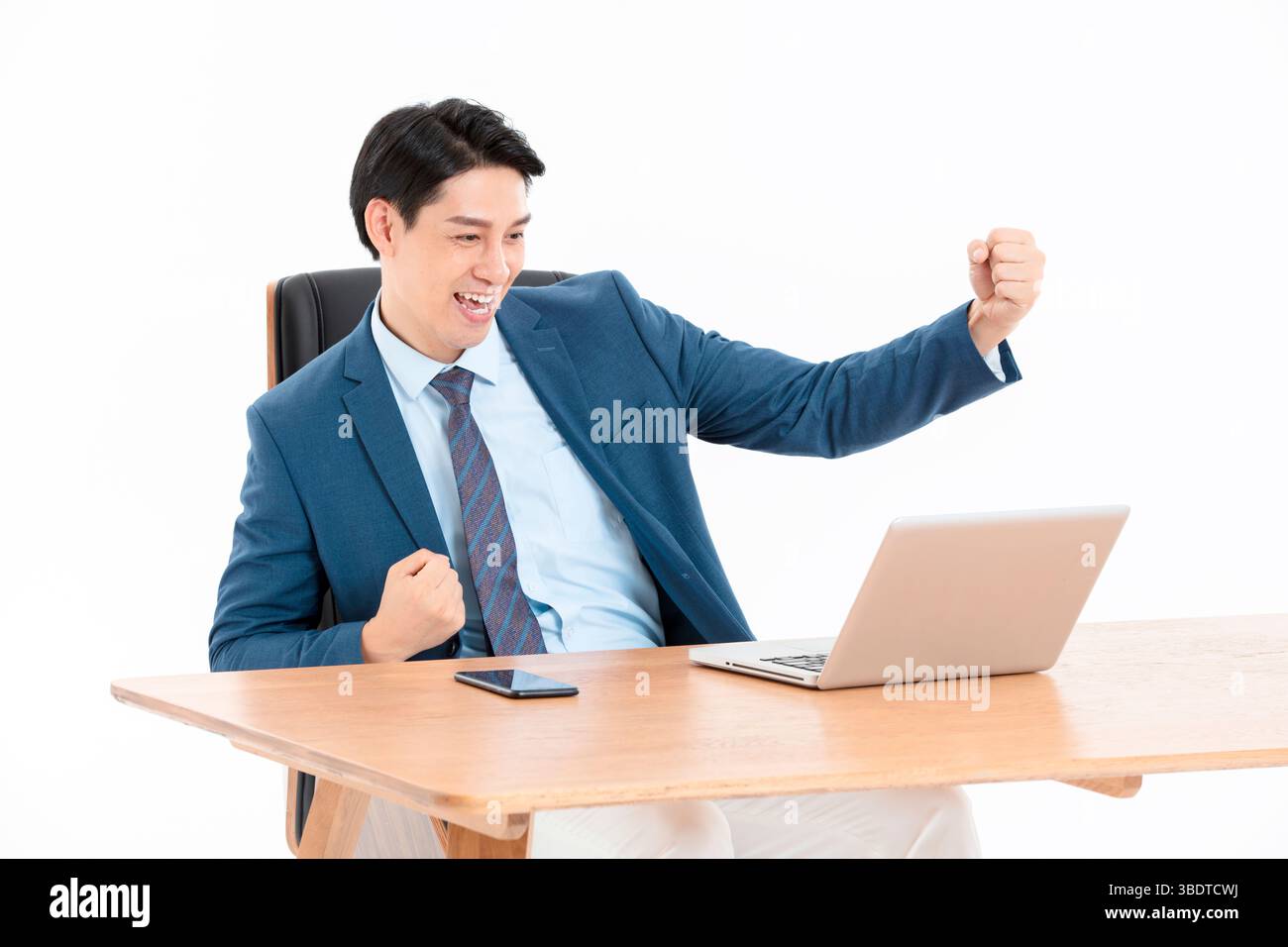 a young suited man excitedly raising both hands at his desk Stock Photo ...