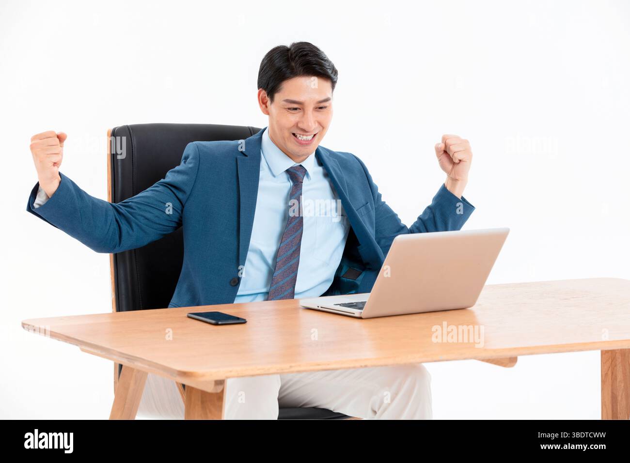 a young suited man excitedly raising both hands at his desk Stock Photo ...