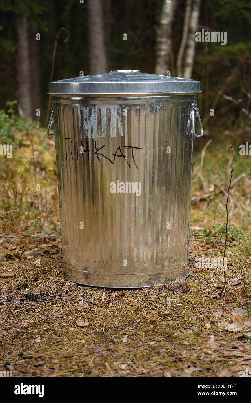 Shiny metal bin labeled "tuhkat" (ashes) near a forest in Finland Stock ...