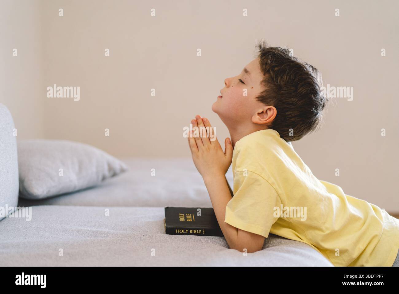 A boy with folded hands in front of him, he prays in his room Stock ...