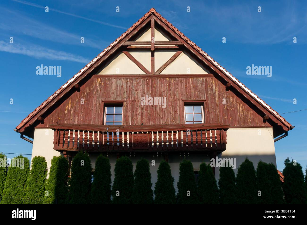 House with gable roof behind fence with emerald green arborvitae trees ...