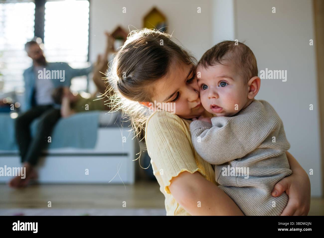 Big sister holding small little brother in her arms, taking care of him ...