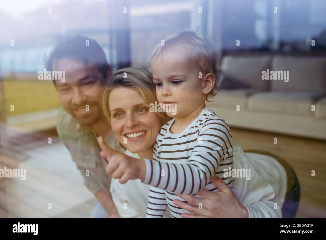 Parents looking out of window with little son, lying on floor Stock ...