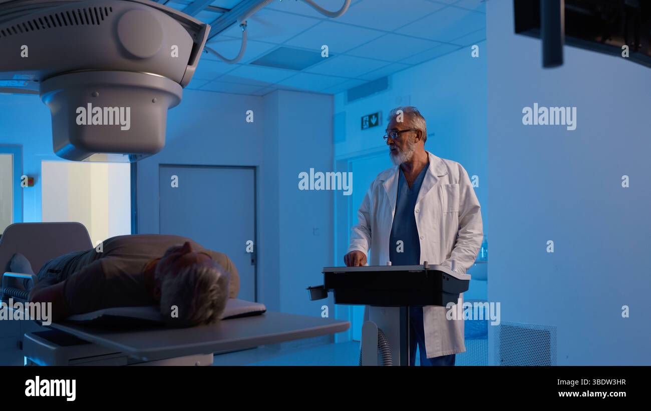 Male patient undergoing X-ray examination using tilting radiographic ...