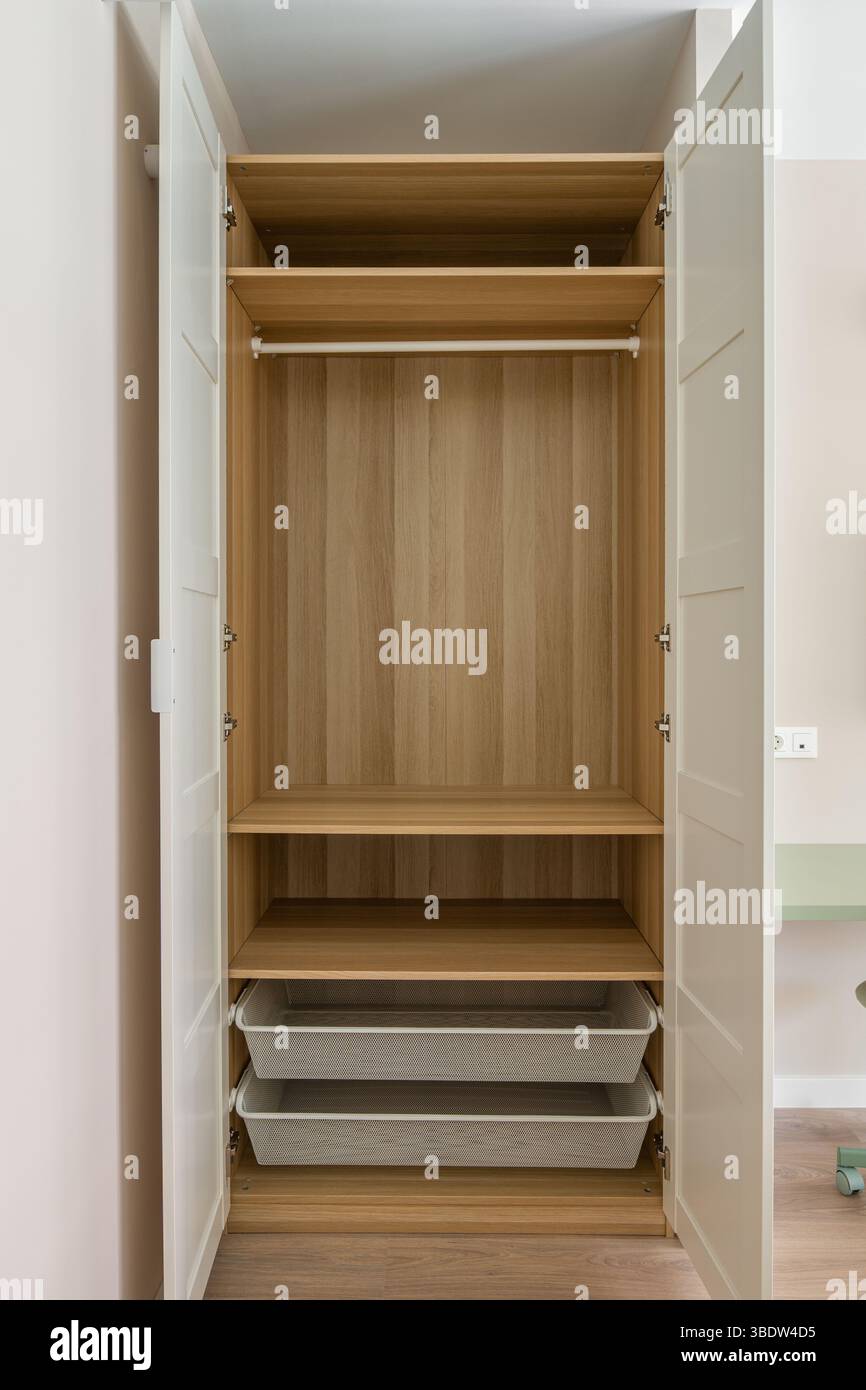 Interior view of empty wooden wardrobe with white doors open showing ...