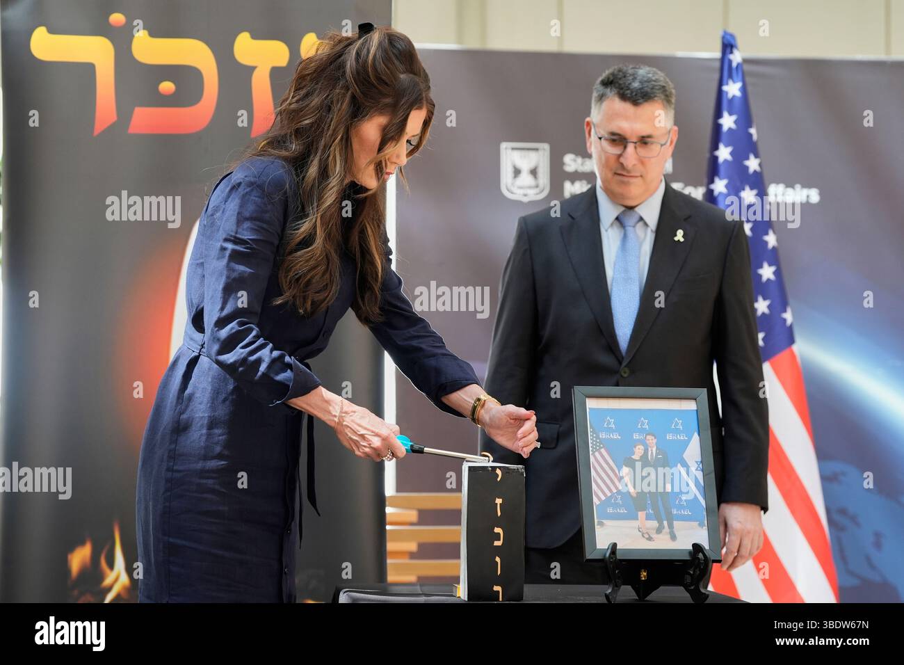 U.S. Homeland Security Secretary Kristi Noem lights a candle during a ...