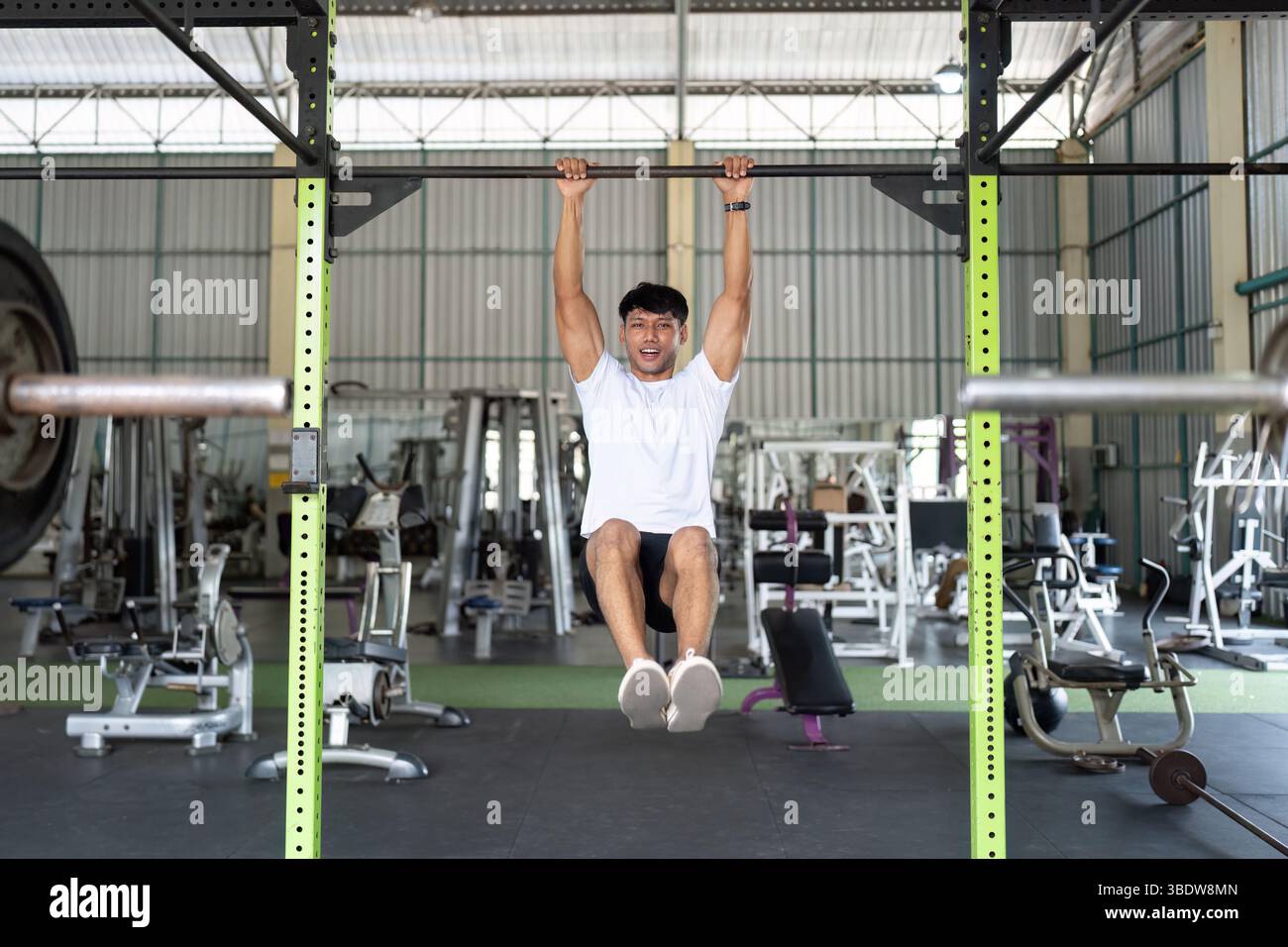 Fitness Enthusiast: Young Man Hanging on Gym Bar, Smiling Stock Photo ...