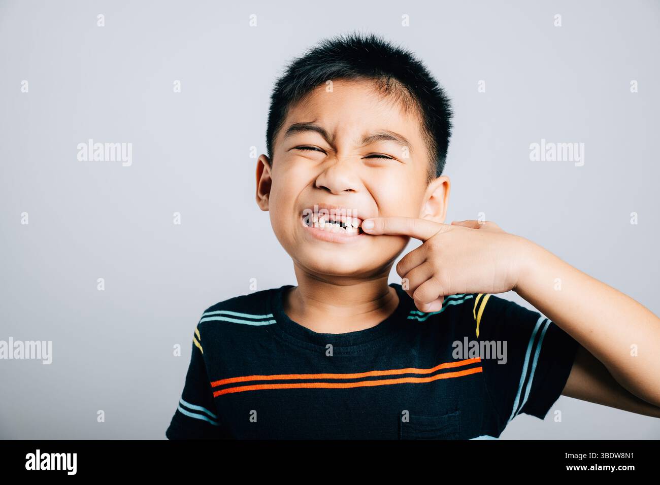 Child an Asian boy points to missing front tooth symbolizing dental ...