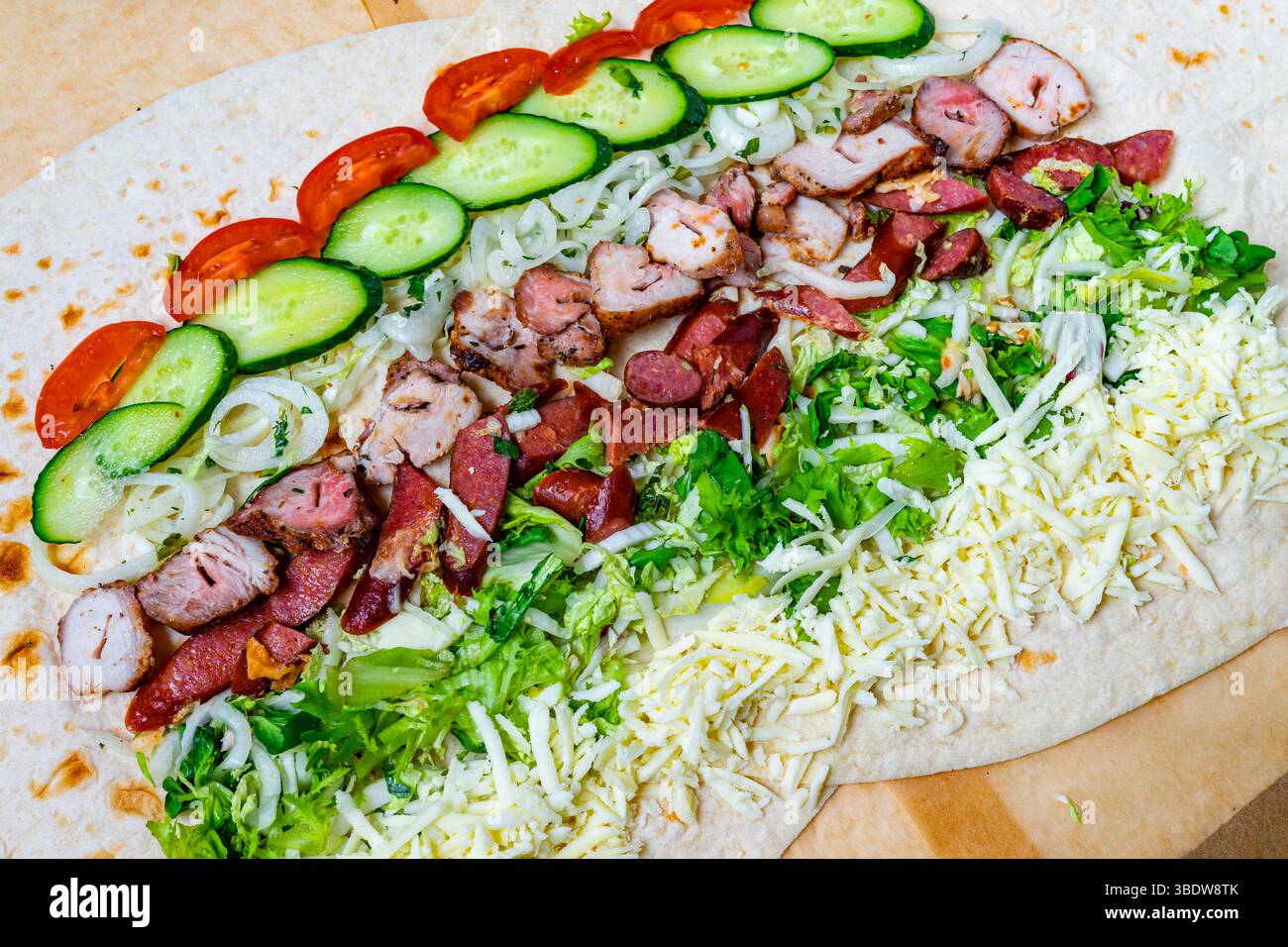 A vibrant wrap is prepared with layers of grilled chicken, various ...