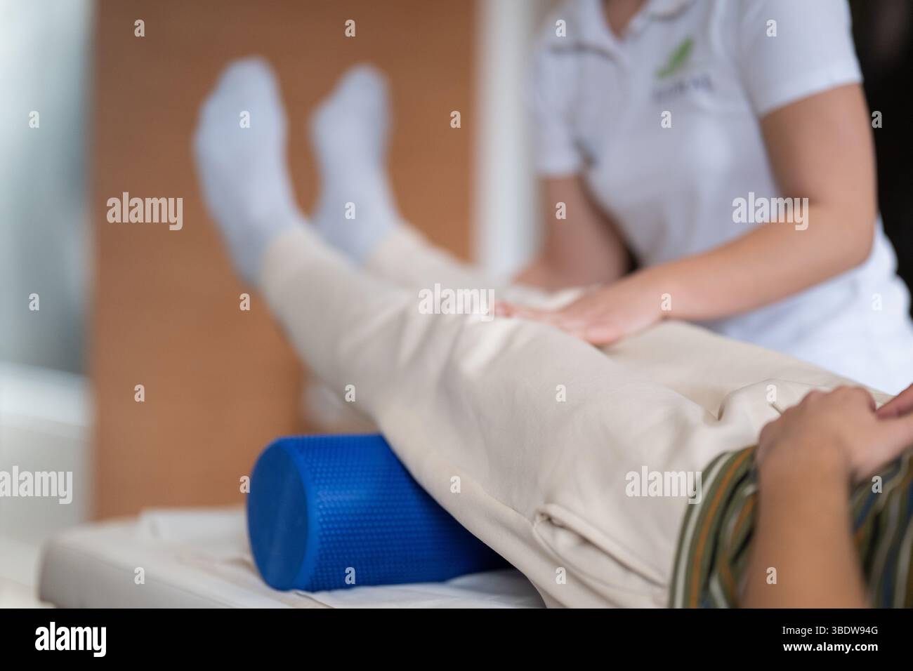 Physiotherapy Session with Blue Foam Roller.A therapist guiding a ...