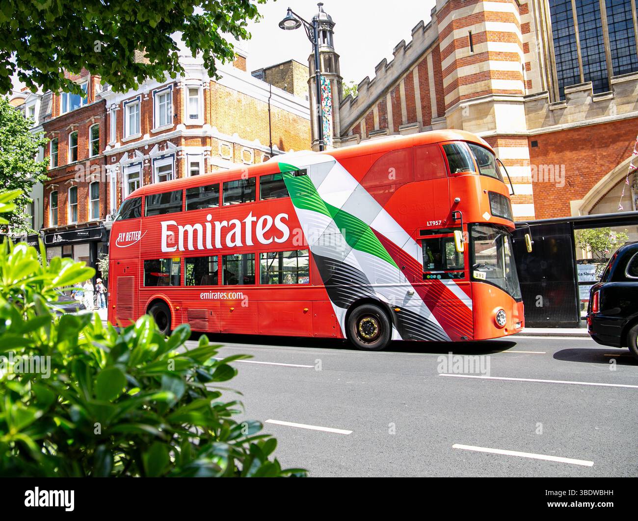 Red London double-decker bus with Emirates branding on a city street ...