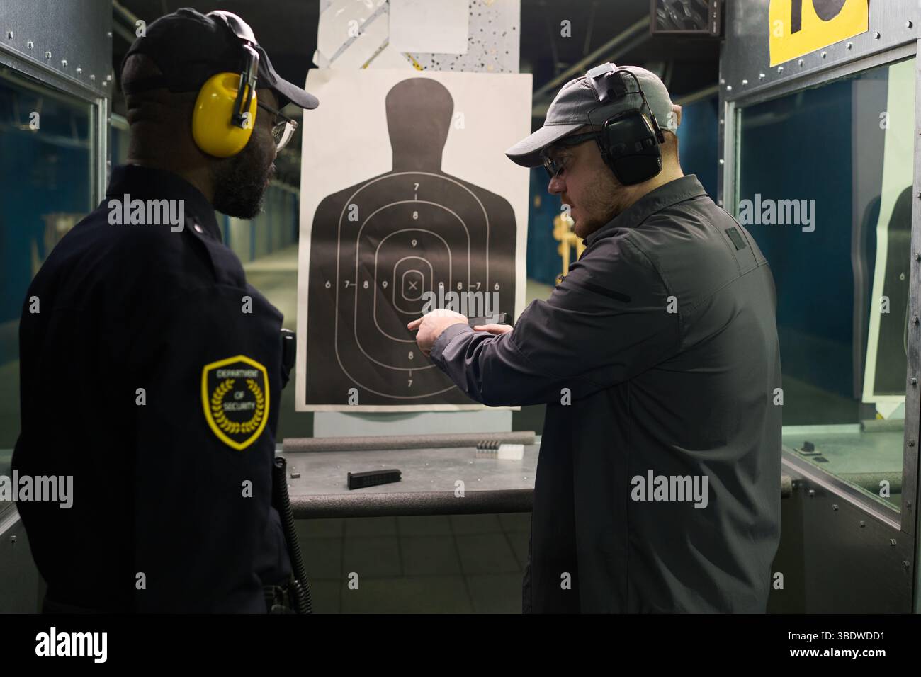 Law enforcement officer instructing a person at indoor shooting range ...