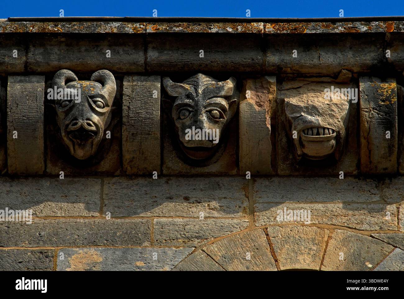 Sabre-toothed mouth and two horned beast among sculpted grotesque faces ...