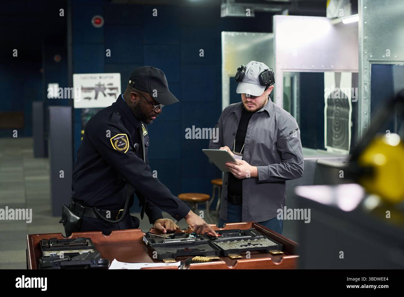 Officer and man collaborating in indoor shooting range, reviewing ...
