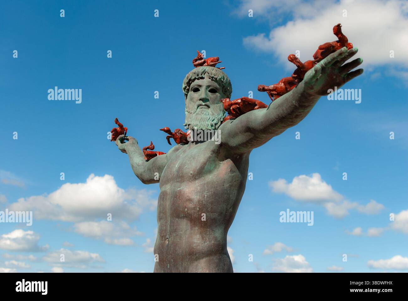 Bronze statue of Greek god with red birds against a blue sky with white ...