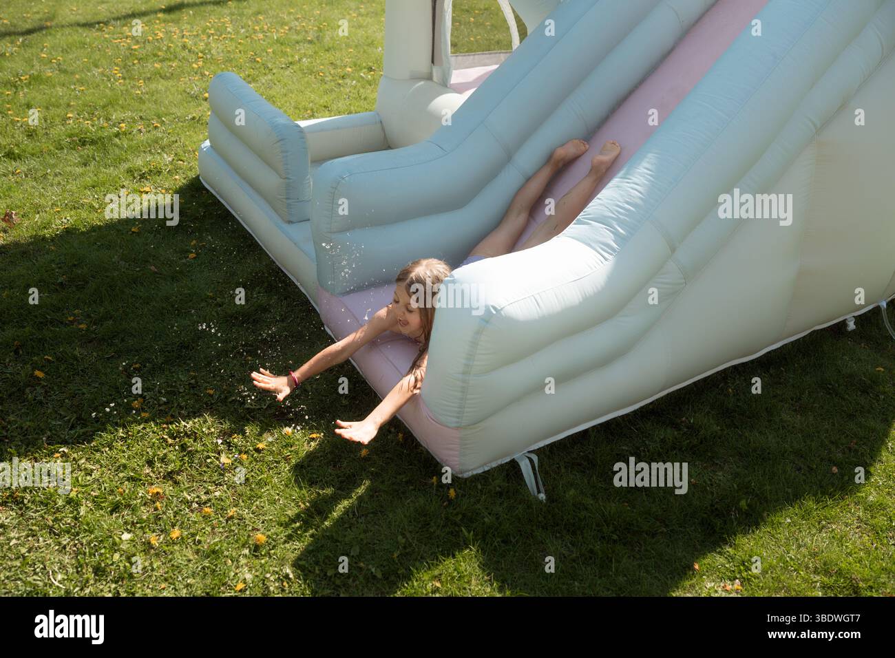 Girl lands face-first from inflatable slide onto grassy backyard Stock ...