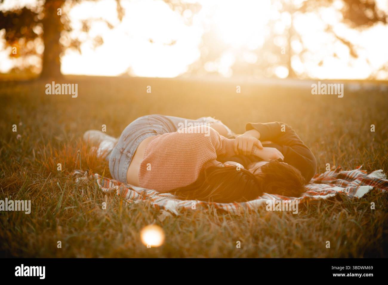 Loving couple cuddles on cozy blanket during golden hour picnic Stock ...