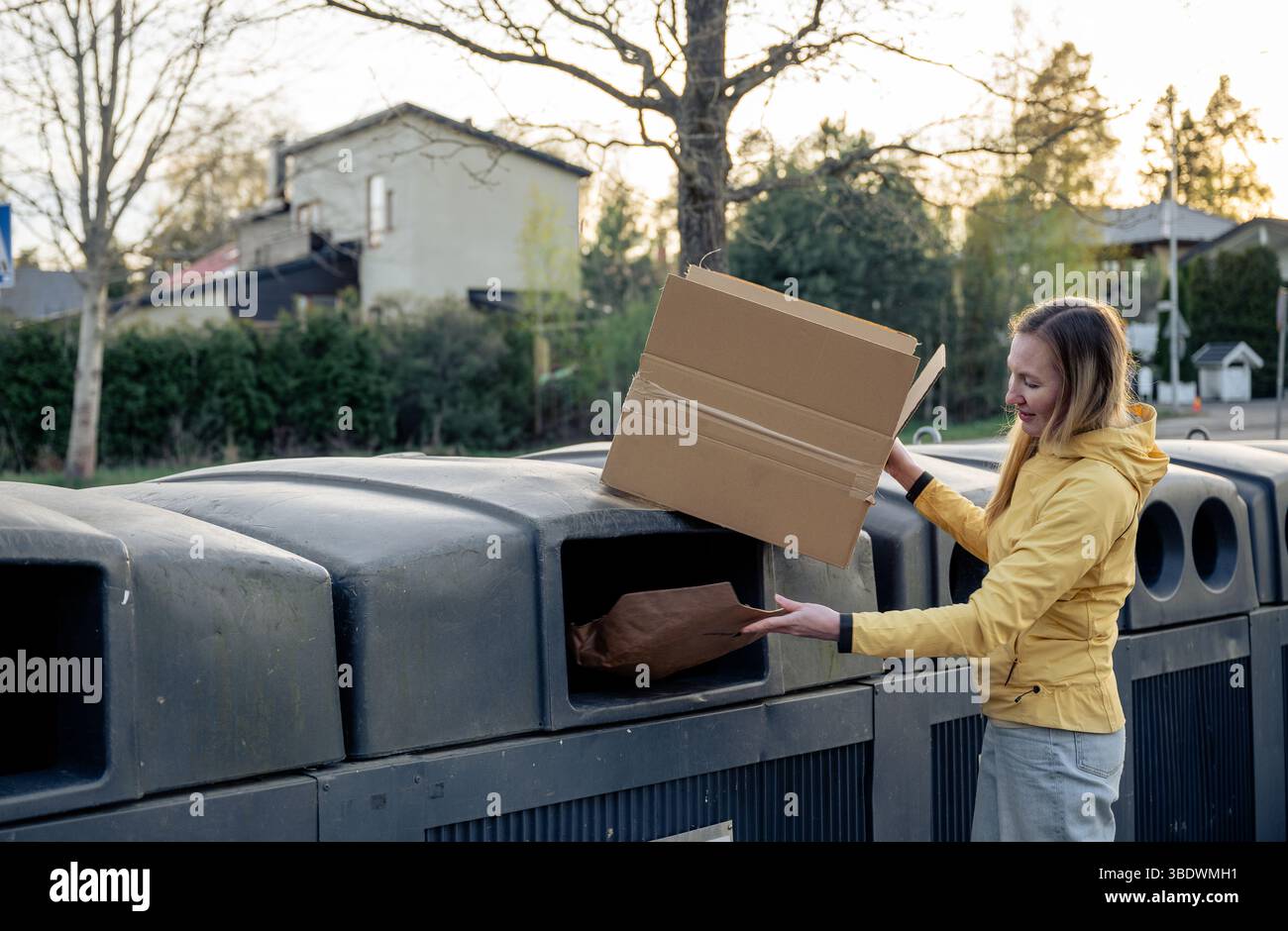 woman puts cardboard trash in outdoor recycling bins Stock Photo - Alamy