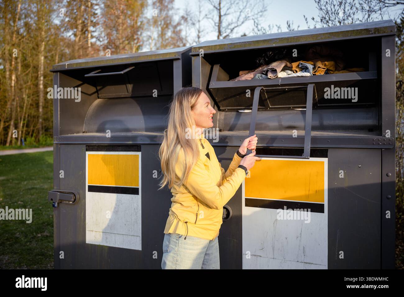 Woman donating old used clothes into recycling container outdoors Stock ...