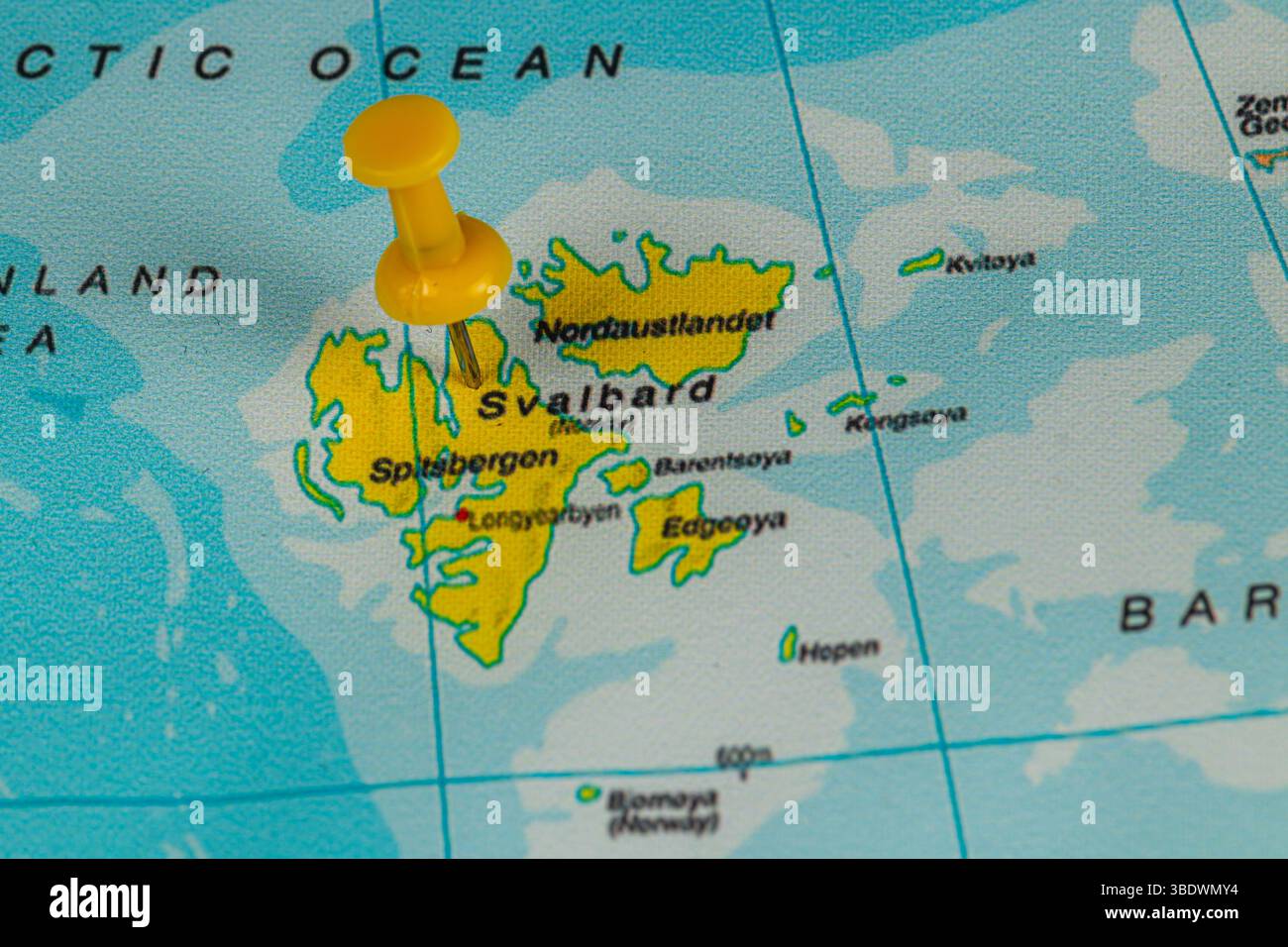 A yellow pushpin marks Svalbard Island on a detailed map. The coastal ...